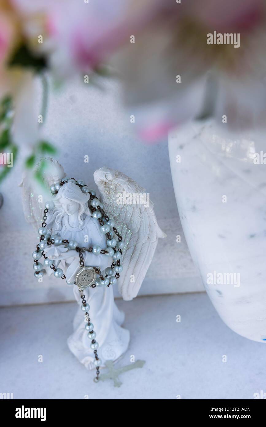 Small angel figure, hung with a rosary chain on an urn grave in a ...