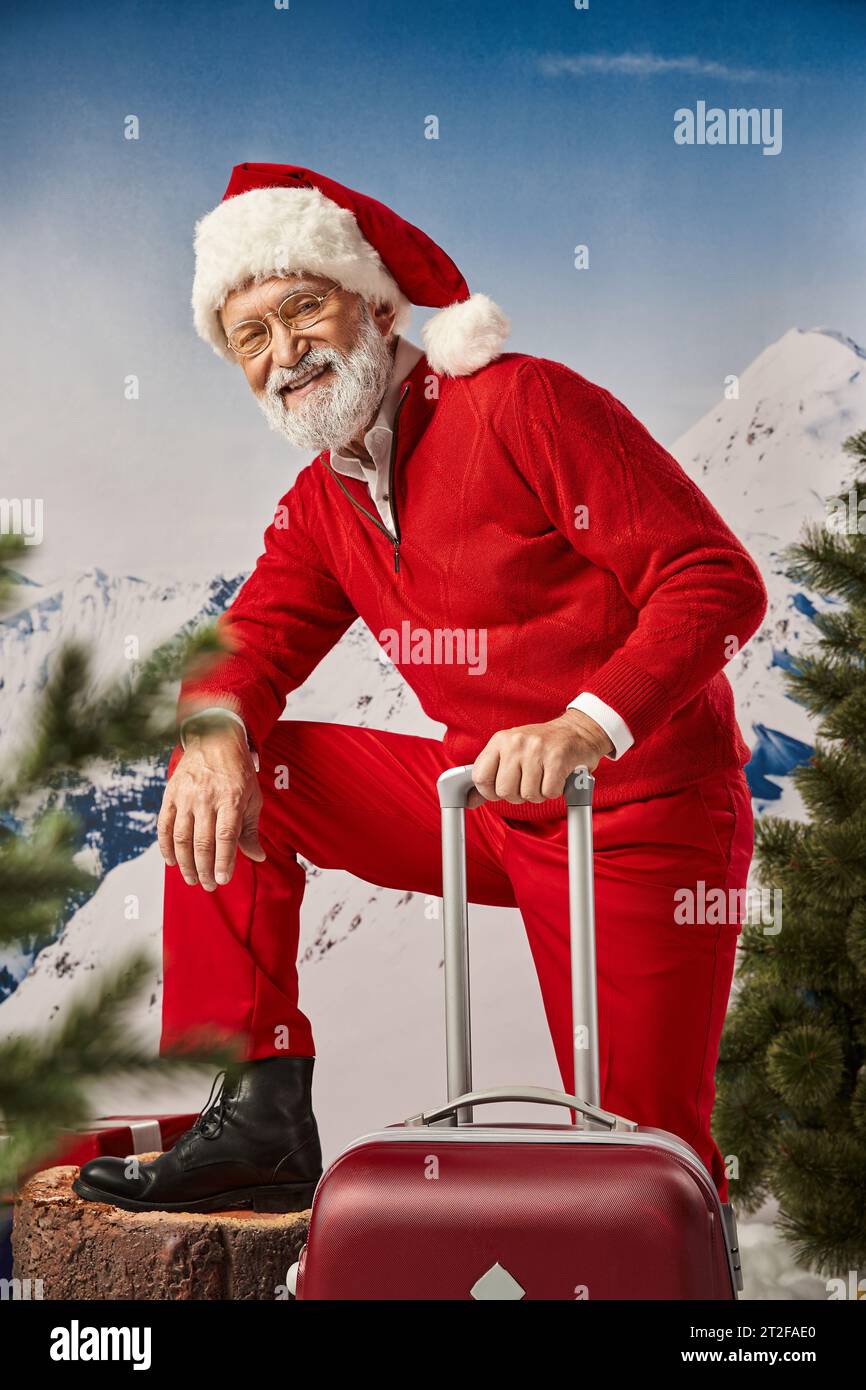 joyful man dressed as Santa in glasses posing with suitcase looking at ...