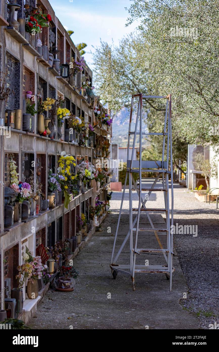 Wall with graves and ladder with wheels in a cemetery, Bari Sardo ...