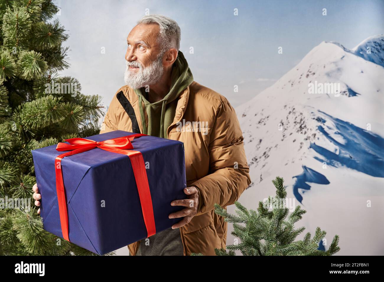 Cheerful man dressed like Santa in warm sporty jacket holding present ...