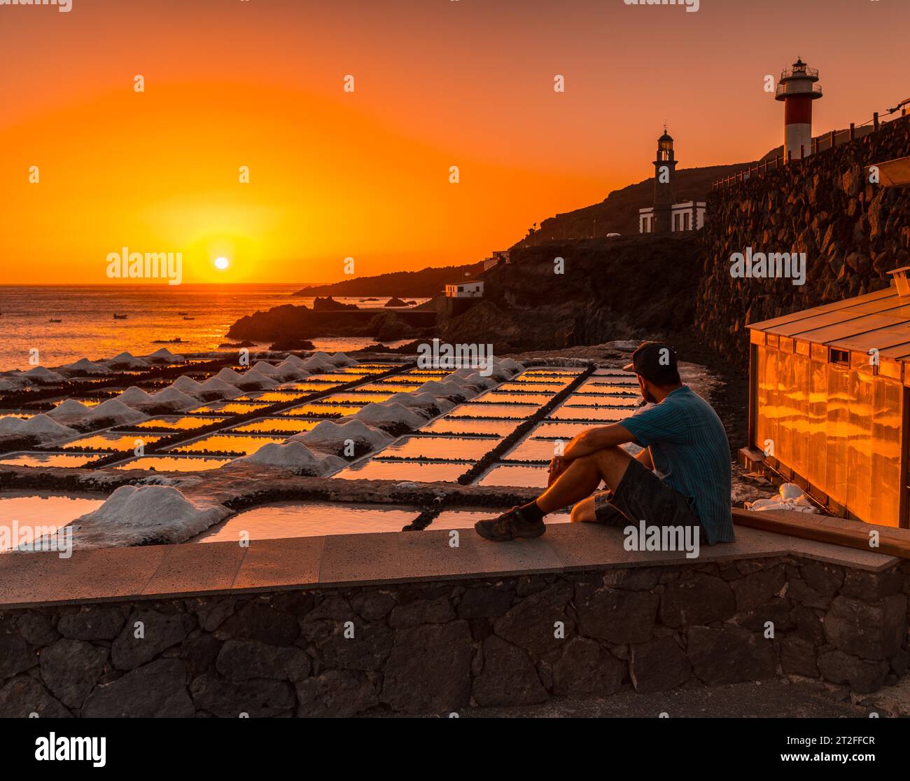 A young man sitting in the sunset of the Fuencaliente Lighthouse next ...