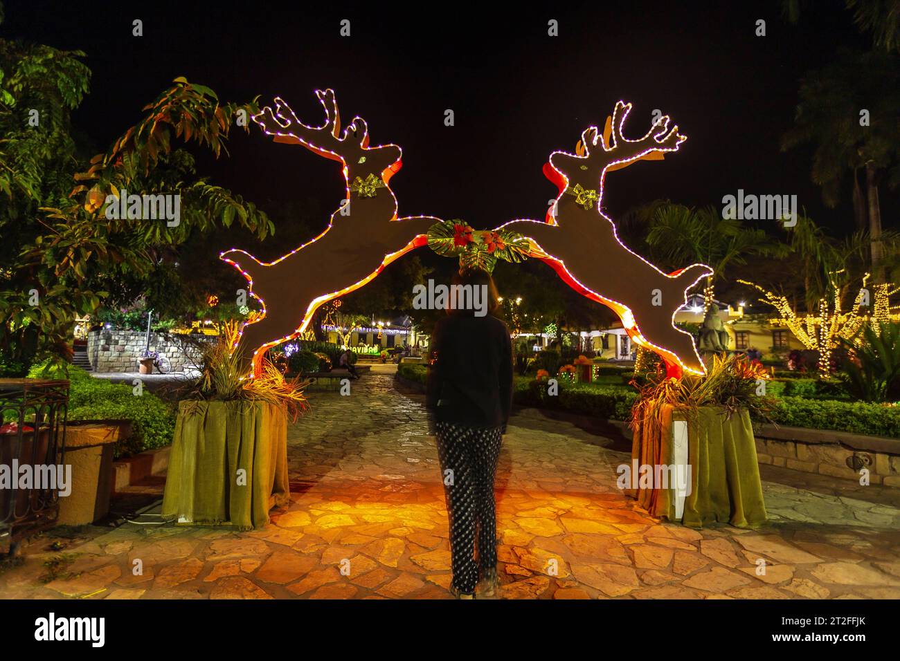 A young woman passing a reindeer arch at Christmas in Copan Ruinas ...