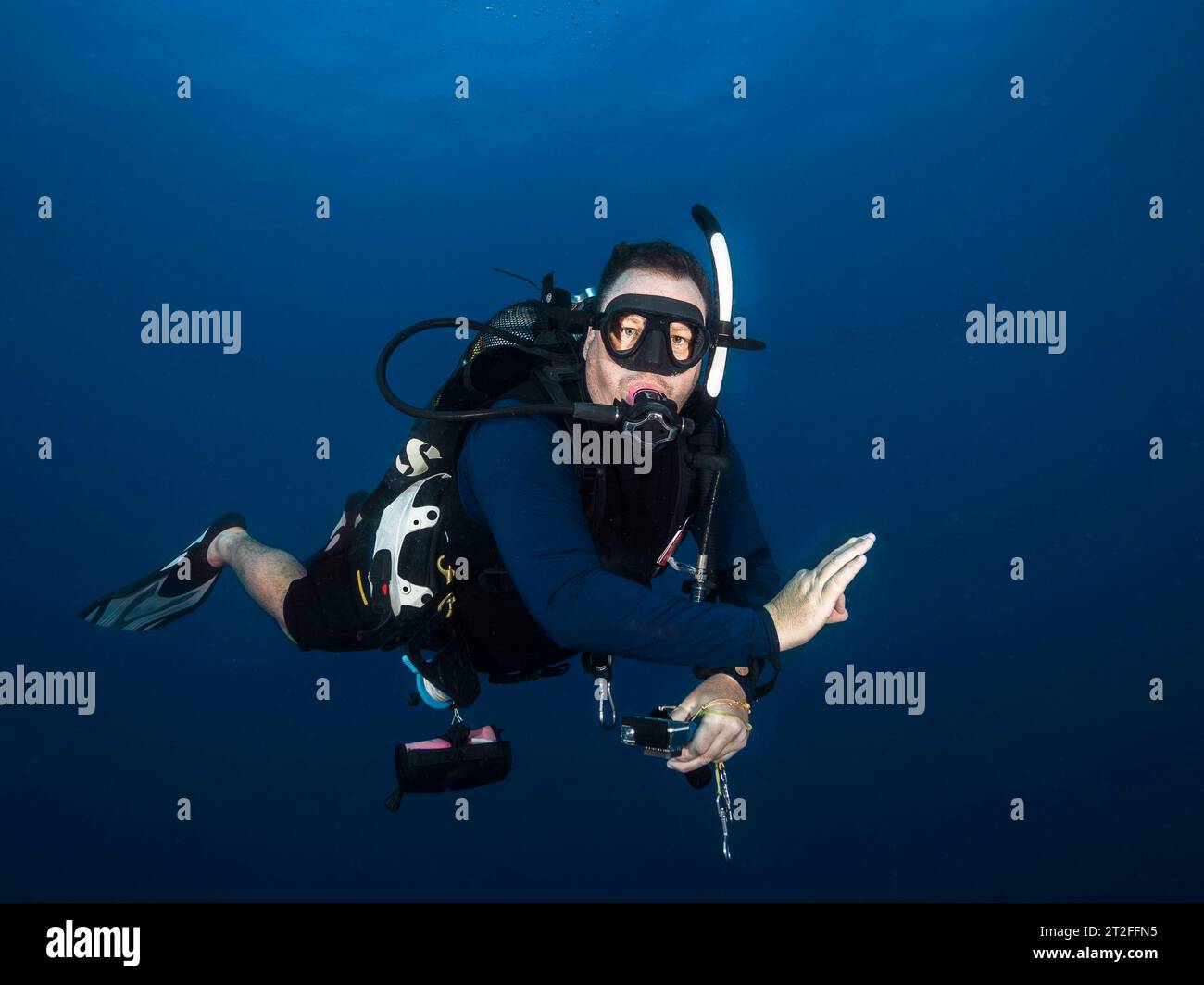 Closeup of a male scuba diver in the deep blue sea looking at the ...