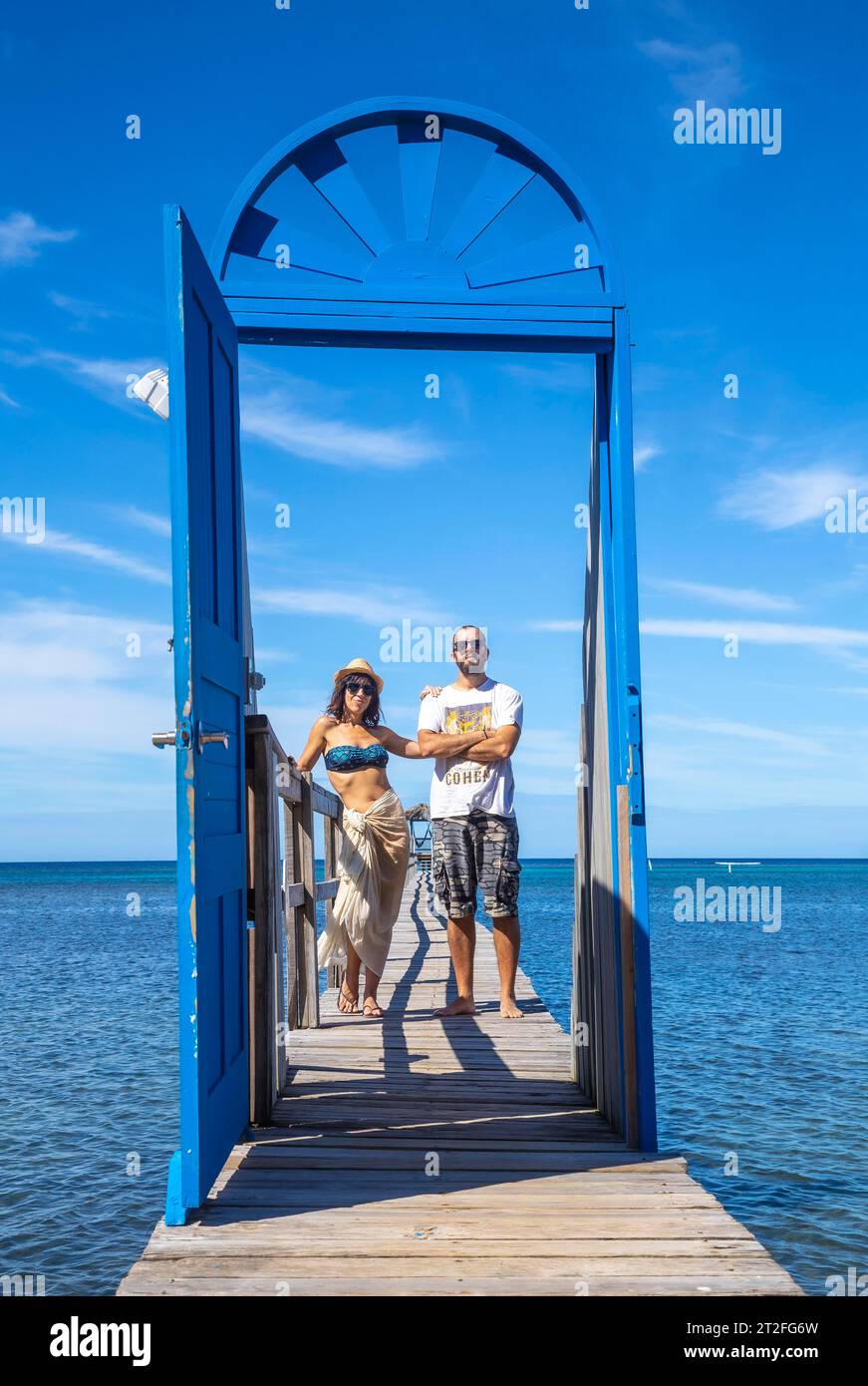 A couple at a blue door on the beach of Sandy Bay on Roatan Island ...