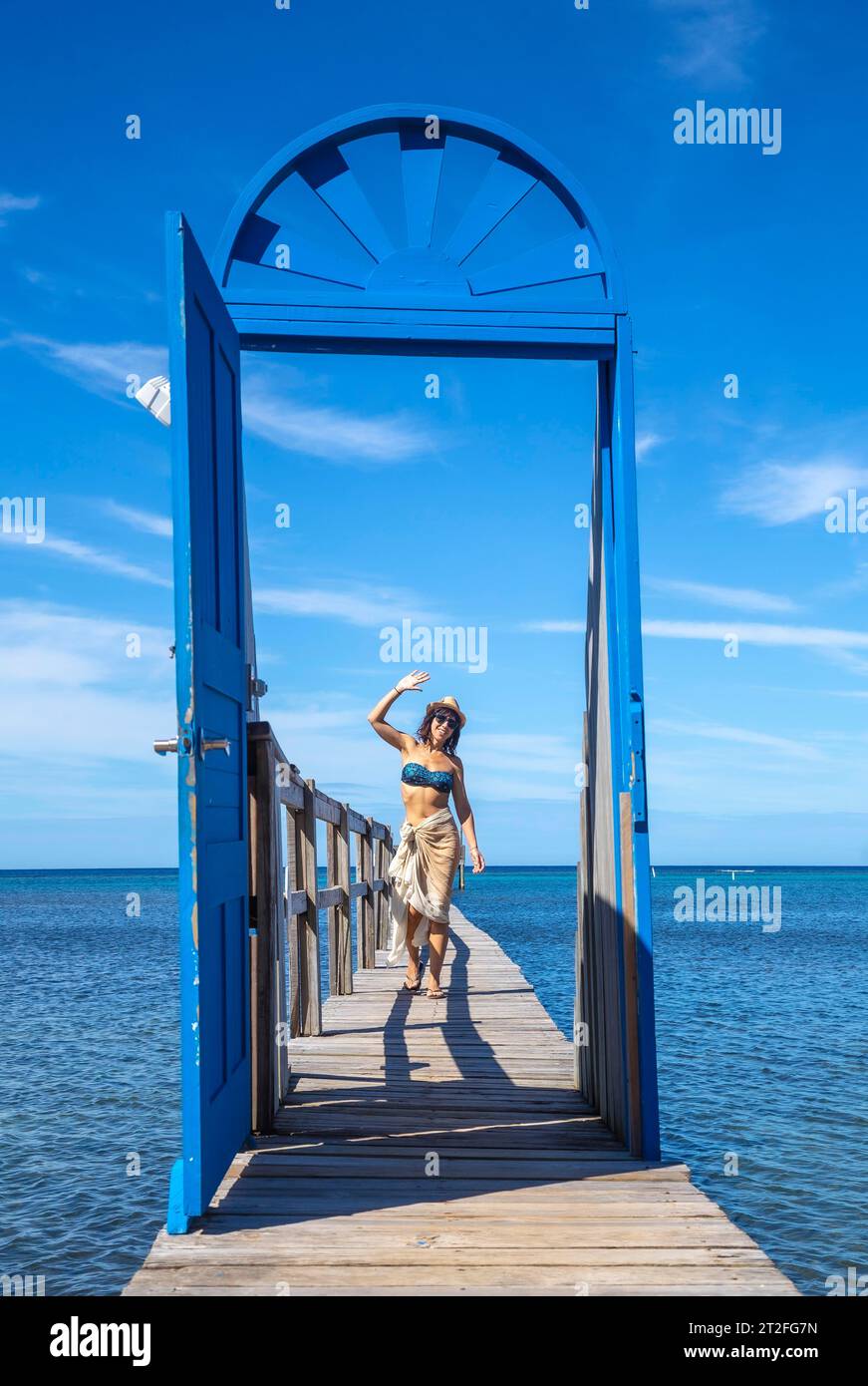 A cheerful young girl at a blue door in the Caribbean Sea on Roatan ...