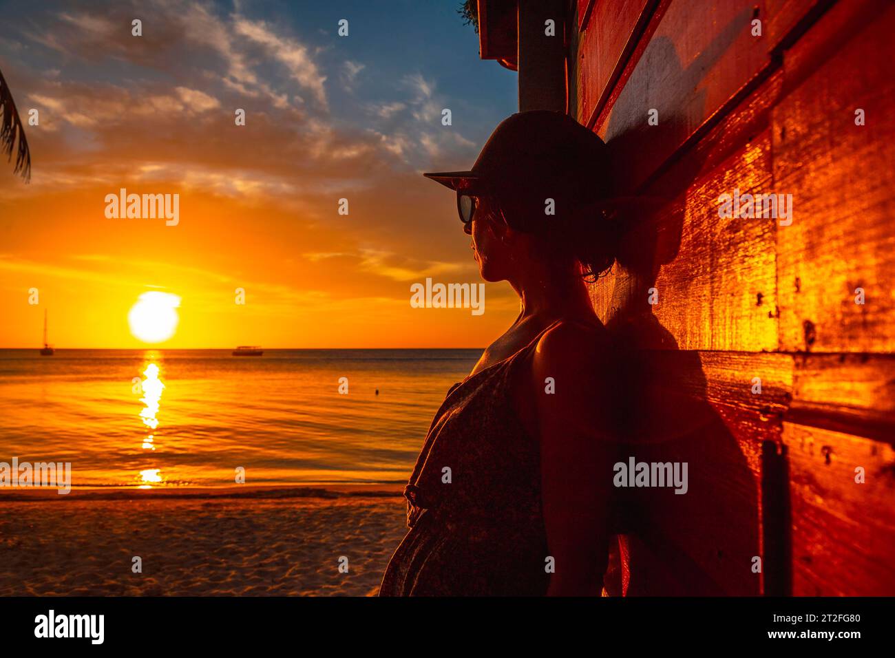 A young woman with a cap at Sunset on West End Beach, Roatan Island ...