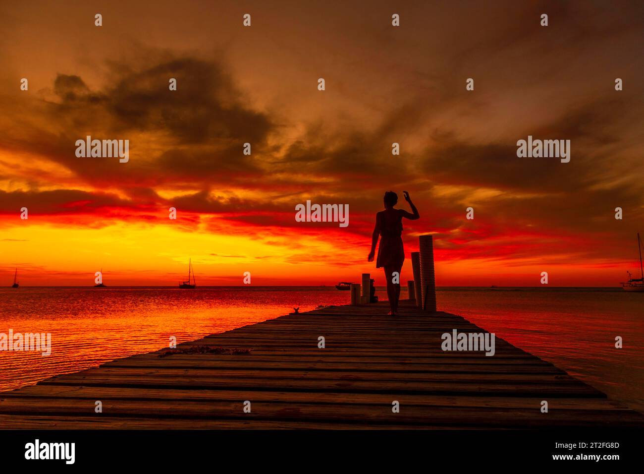 A young woman walking in the sunset on West End beach in Roatan Stock ...