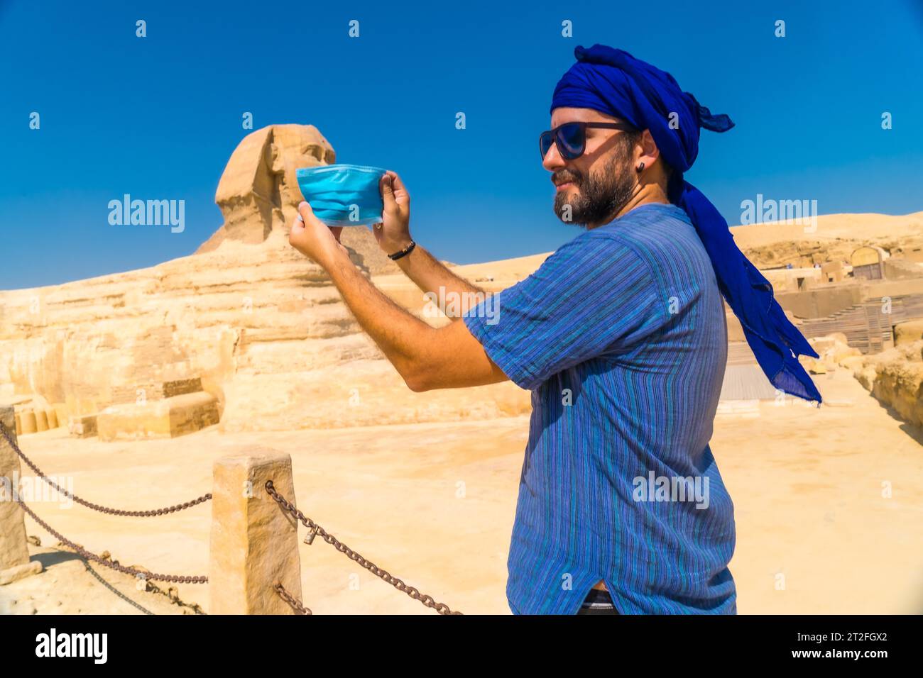 A young man putting on the mask facing the Great Sphinx of Giza and the ...