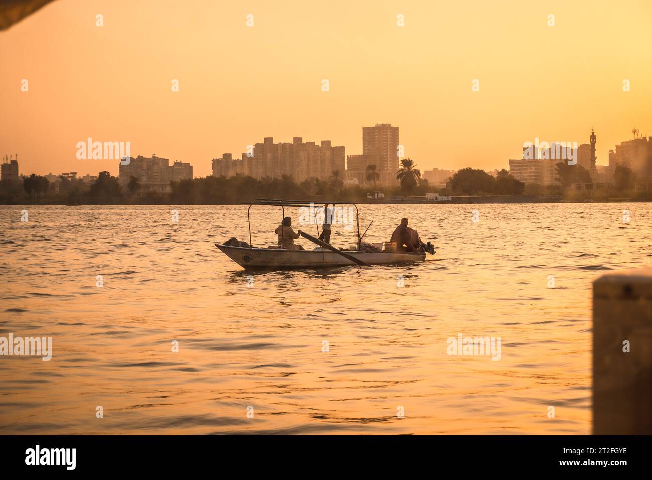 A family of local fishermen at sunset on the Nile river with the city ...