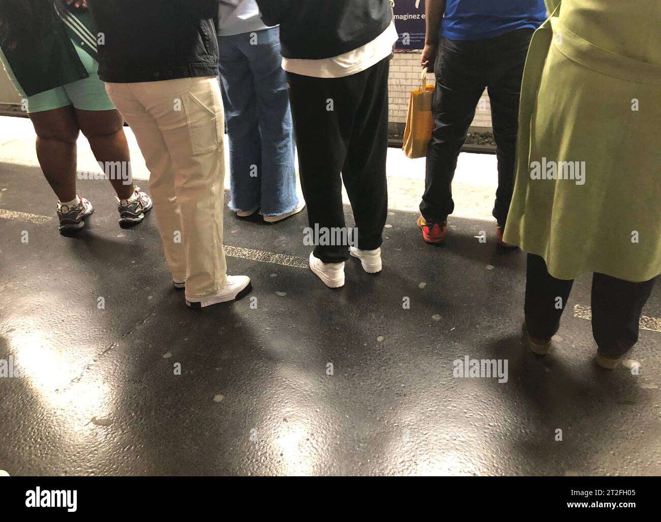 The feet and legs of young people waiting for a subway train in a metro ...