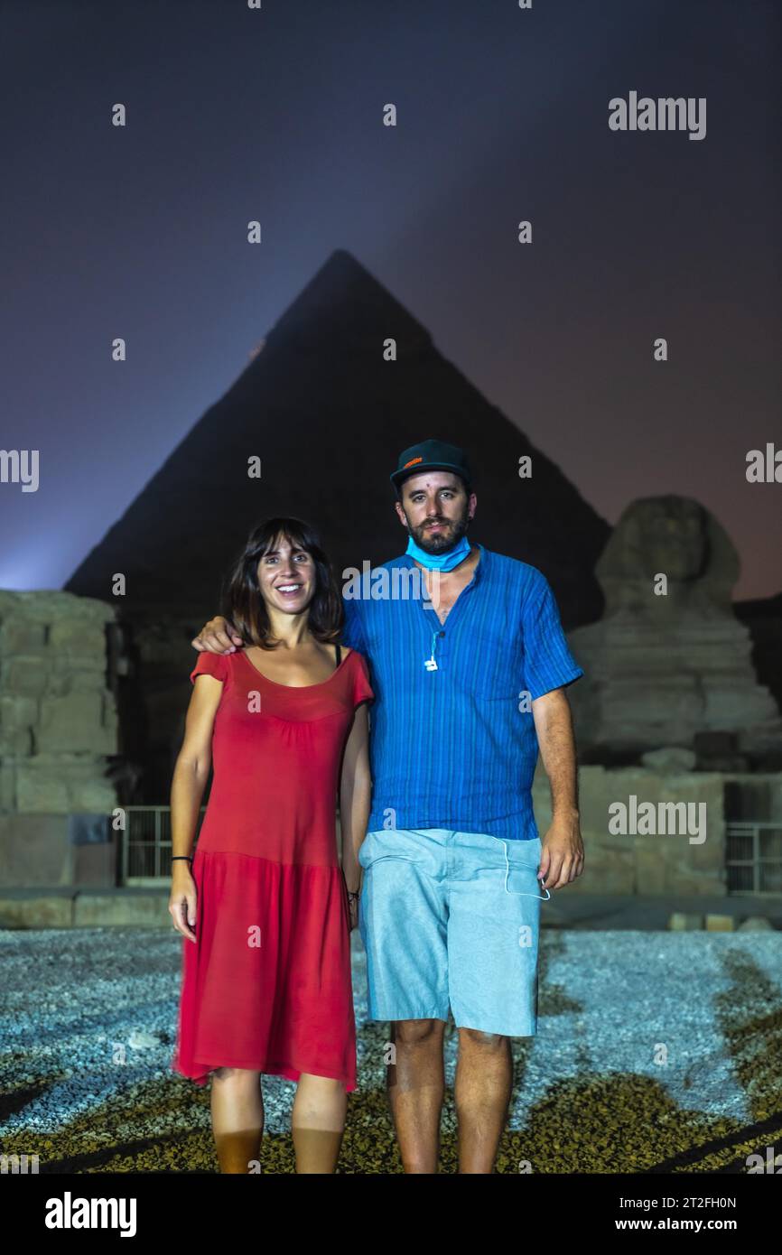 A tourist couple at the sound and light show at the beautiful pyramids and sphinx of Giza. Night ...