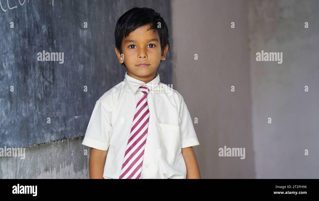 Indian school boy standing against blank chalkboard, intelligent and ...