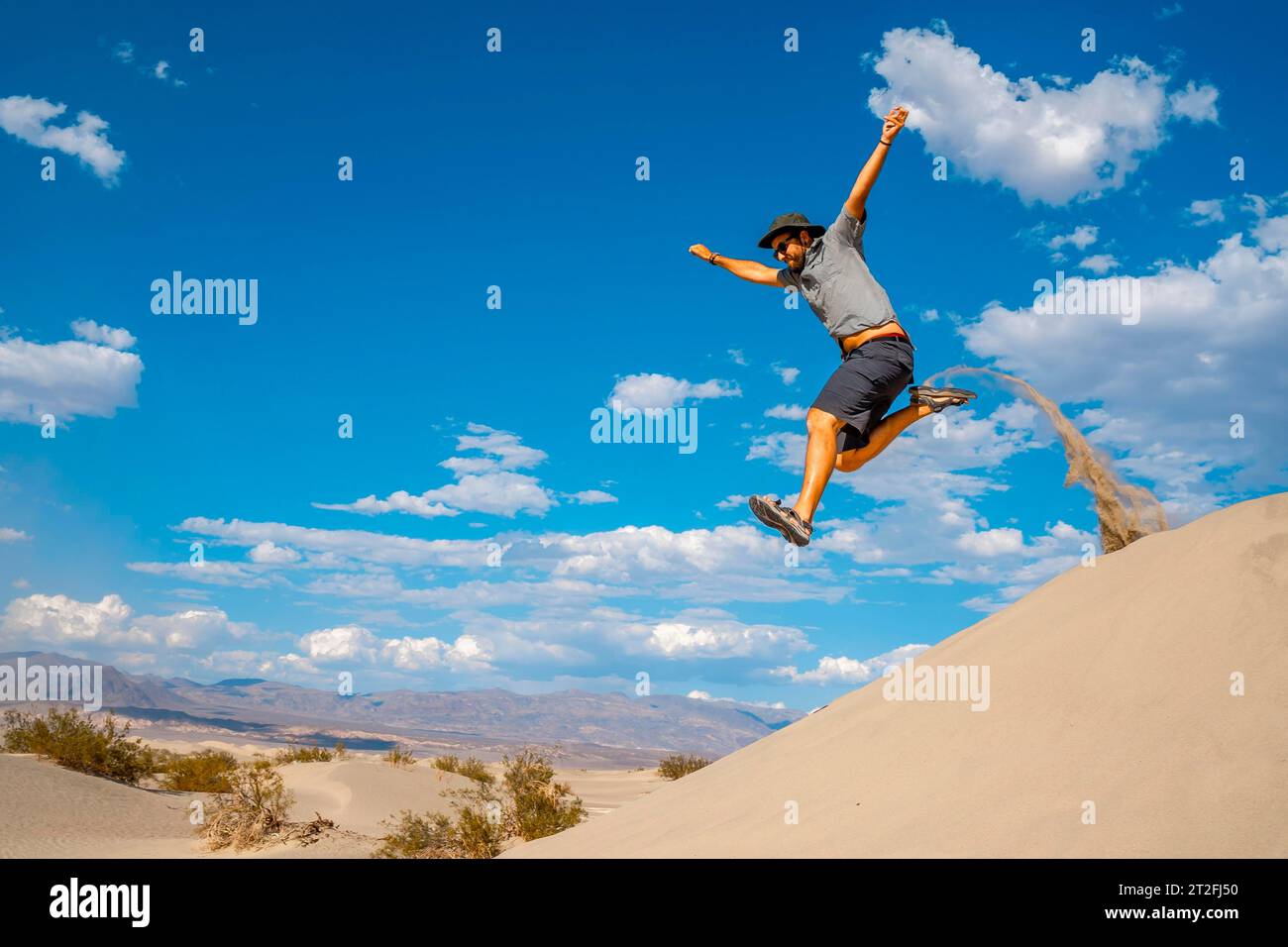 A young man jumping in desert on a summer afternoon in Death Valley ...
