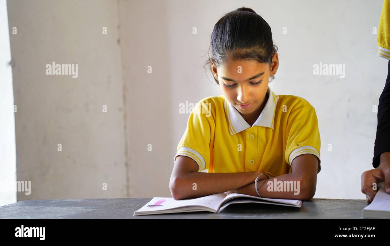 Portrait of happy indian school child sitting at desk in classroom ...