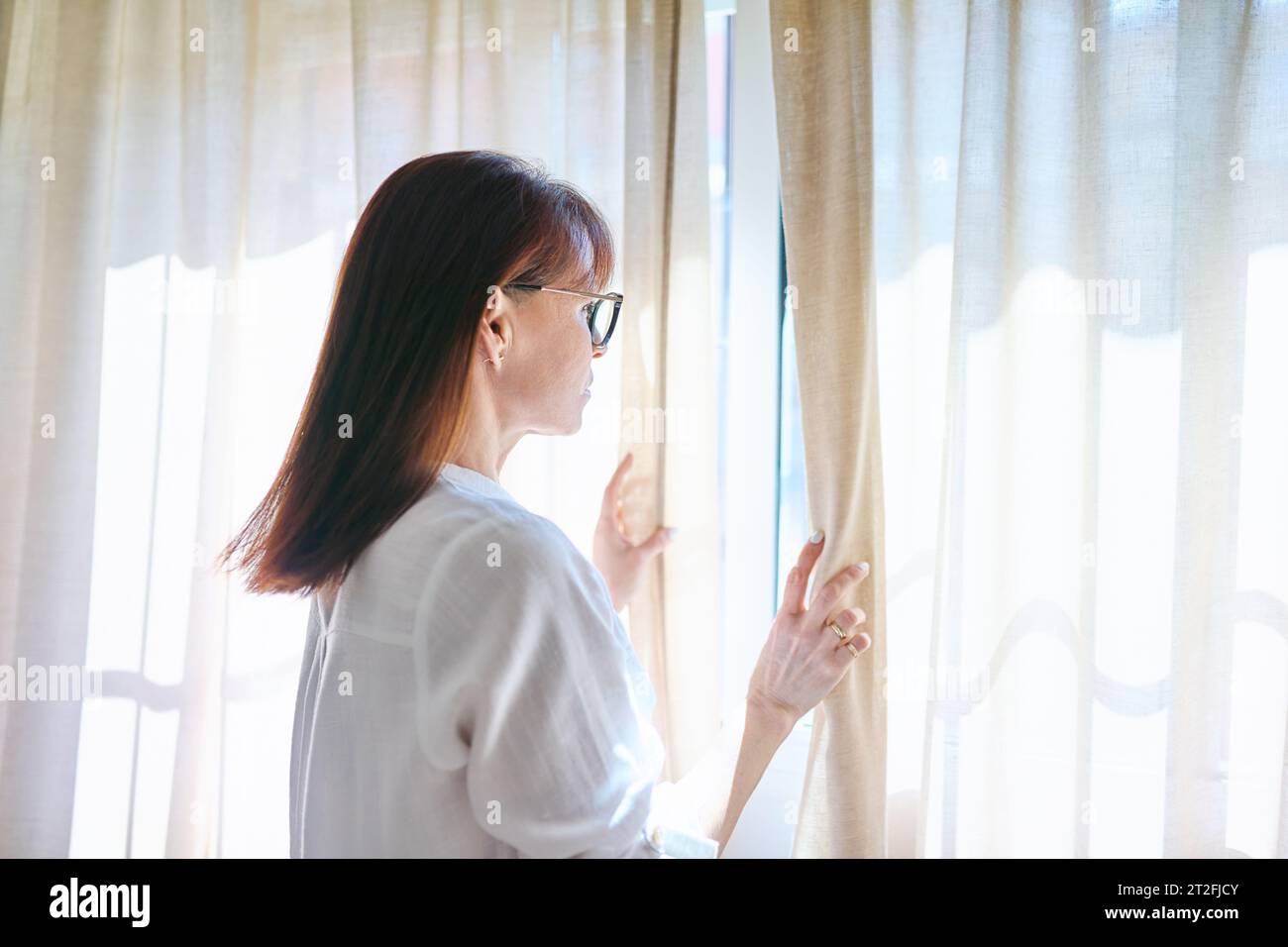 Pensive serious mature woman looking out the window Stock Photo - Alamy