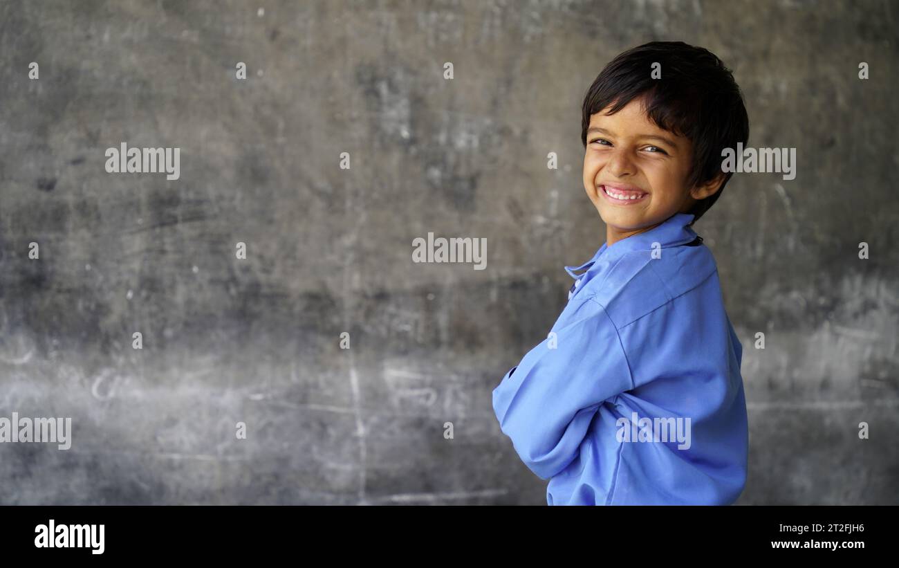 Indian school boy standing against blank chalkboard, intelligent and ...
