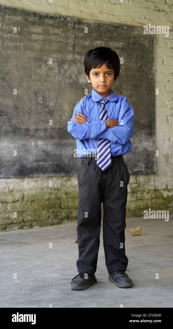 Indian school boy standing against blank chalkboard, intelligent and ...