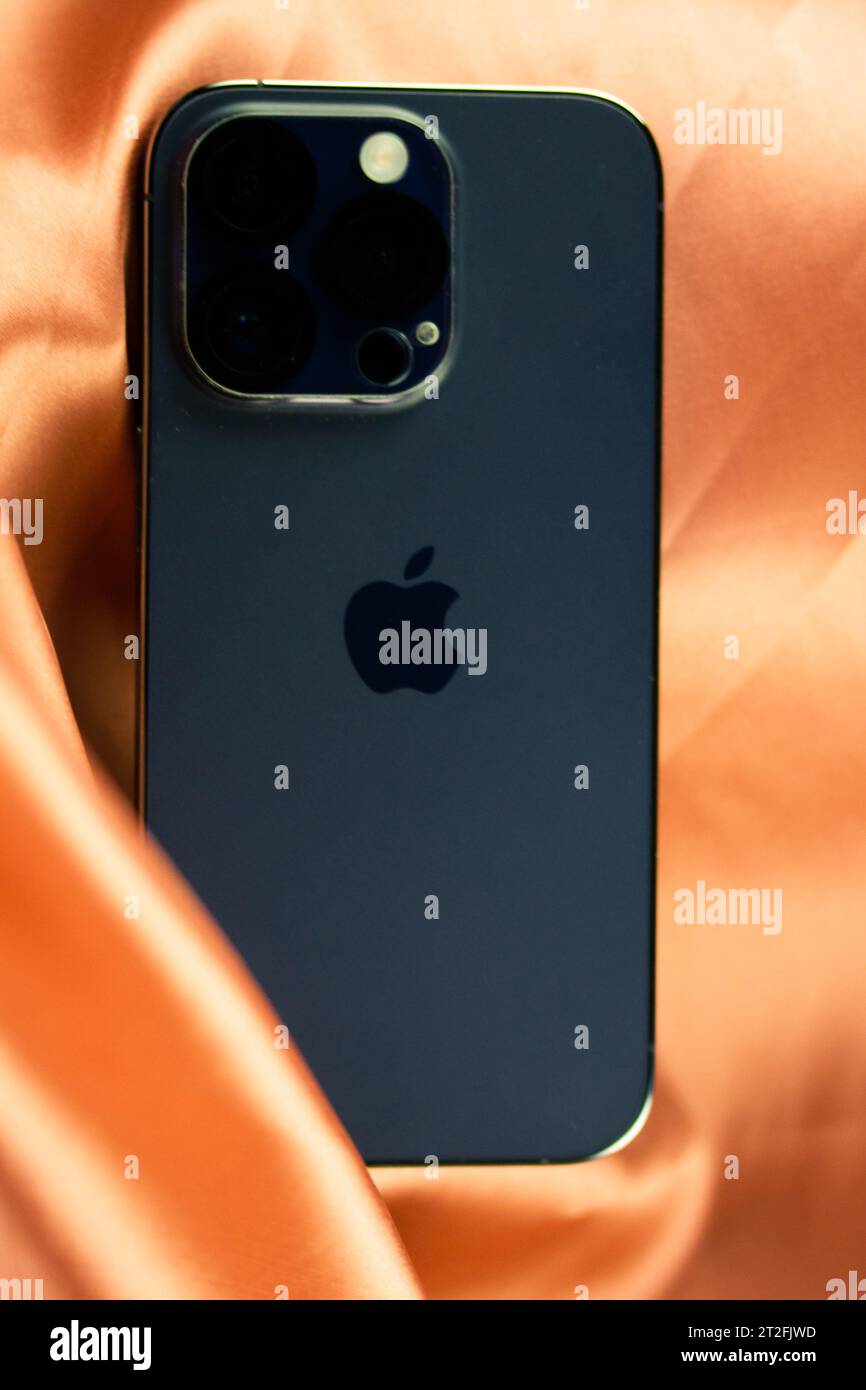 A blue smartphone iPhone 14 PRO back side view on a silk orange ...