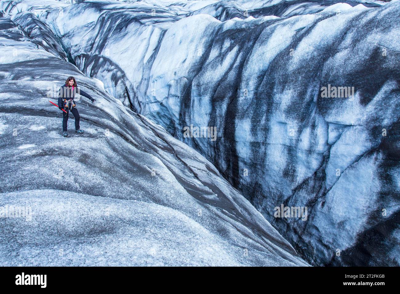 A young woman looking at one of the dangerous ice trekking holes in the ...
