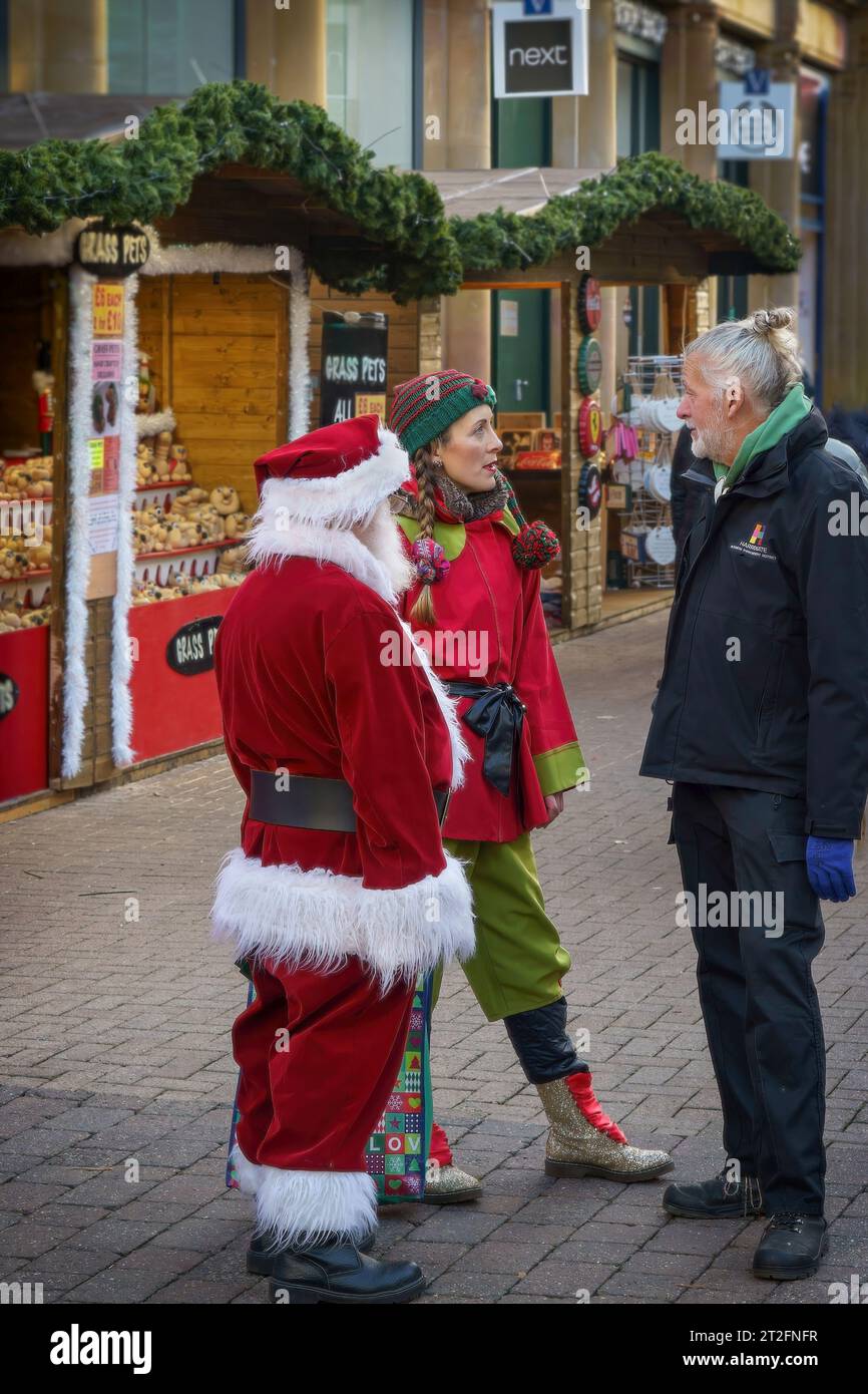 Traditional Father Christmas and an woman dressed as an elf standing ...