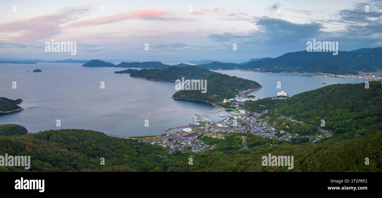Sunrise color in sky over coastal islands and small village on ...
