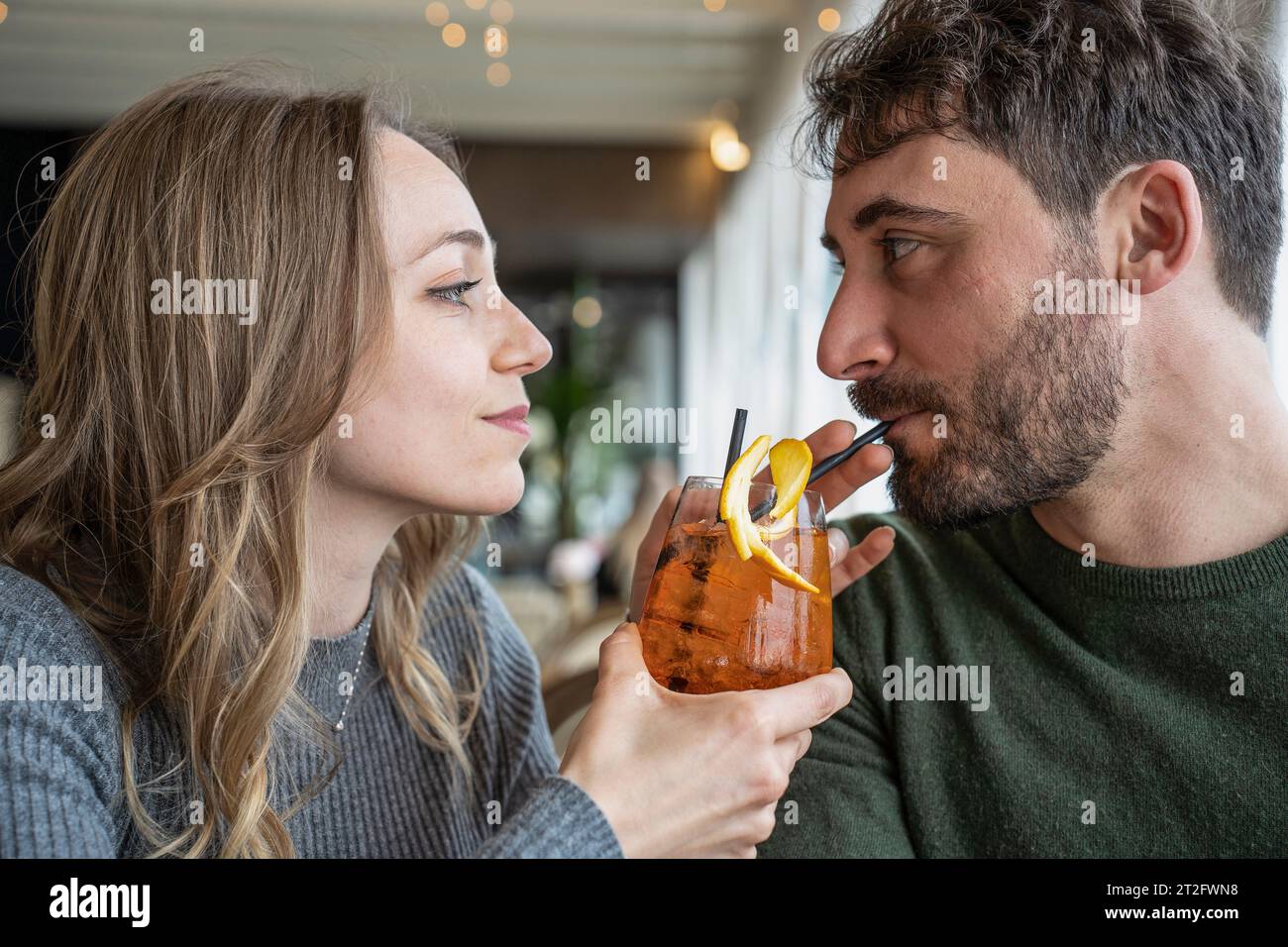 Handsome man and young woman smiling on happy hour at cocktail bar ...