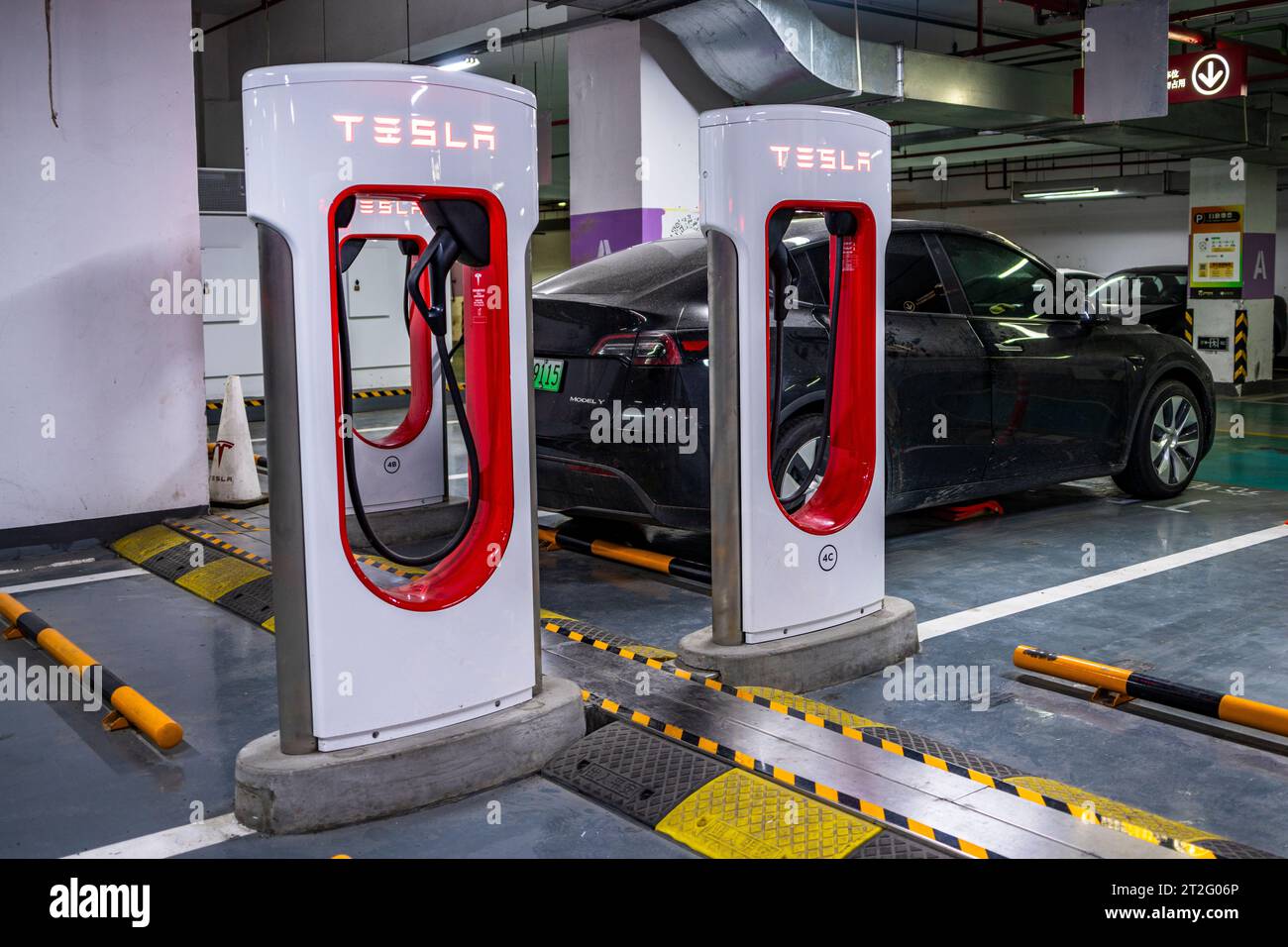 A Tesla Model Y using a supercharger in the underground car park of a ...