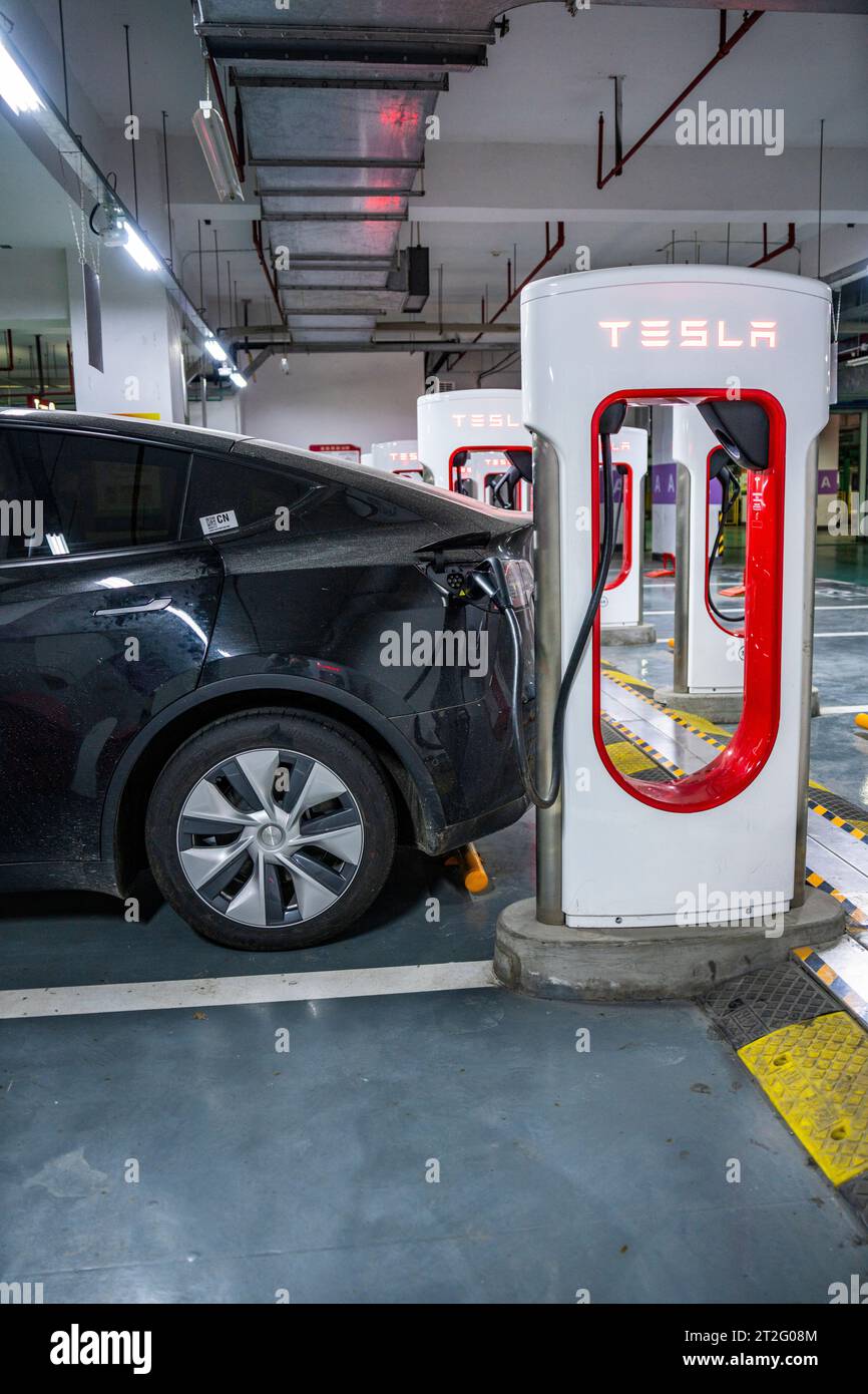 A Tesla Model Y using a supercharger in the underground car park of a ...