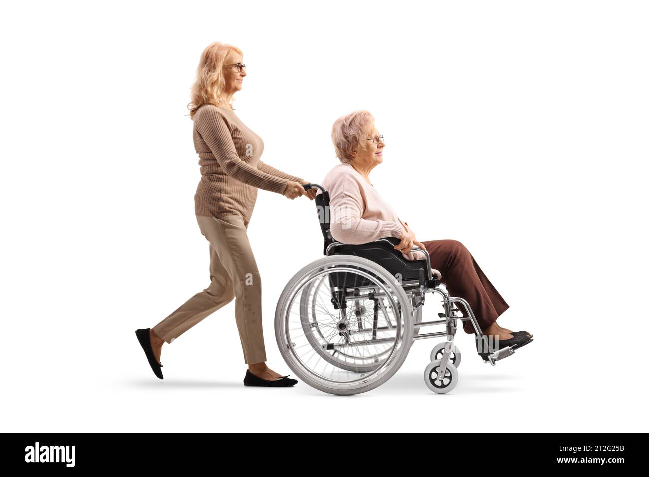 Full length profile shot of a woman pushing an elderly lady in a ...