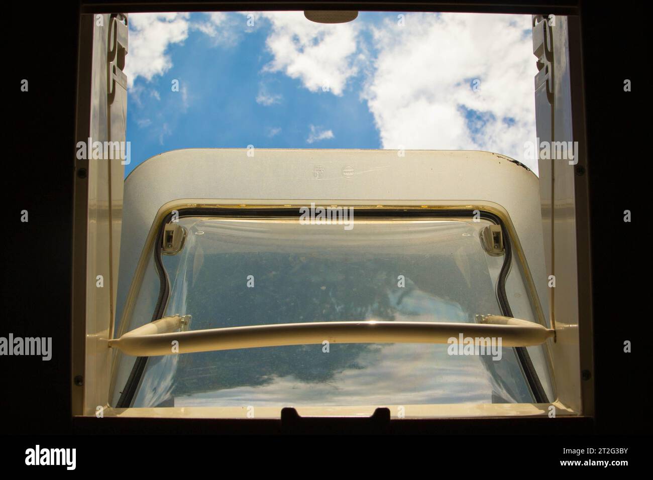 Camper van or motorhome flip out roof window open to see the blue sky ...