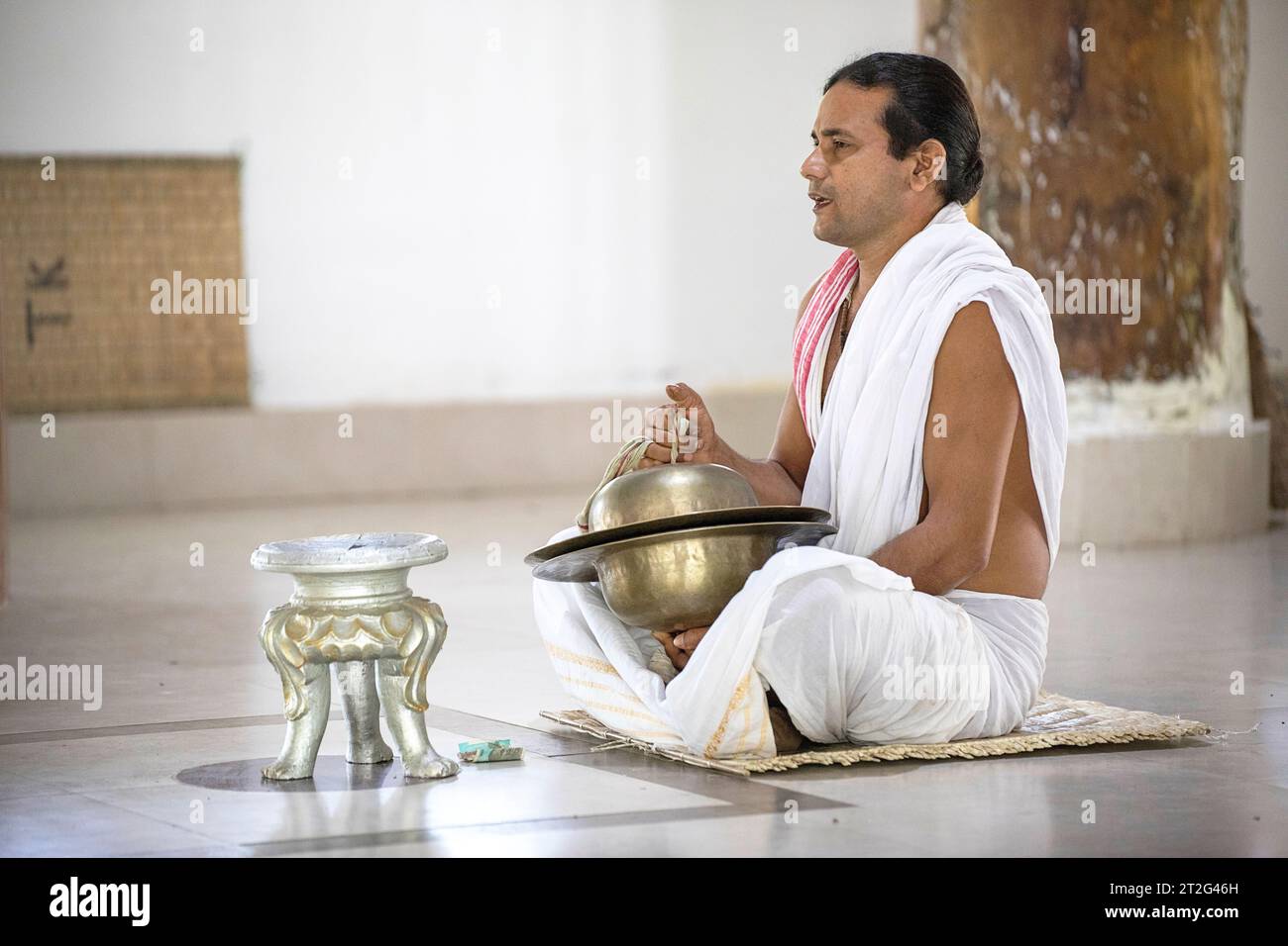 Hindu monk sitting on the floor at the Uttar Kamalabari Hindu monastery, praying and playing on ...