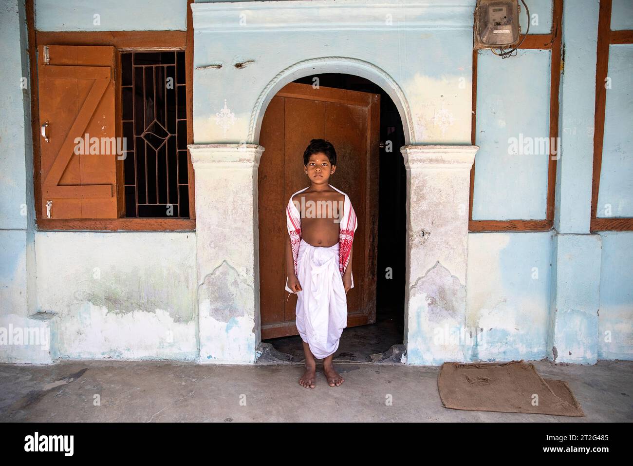 The youngest Hindu monk in traditional clothes standing at the entrance ...