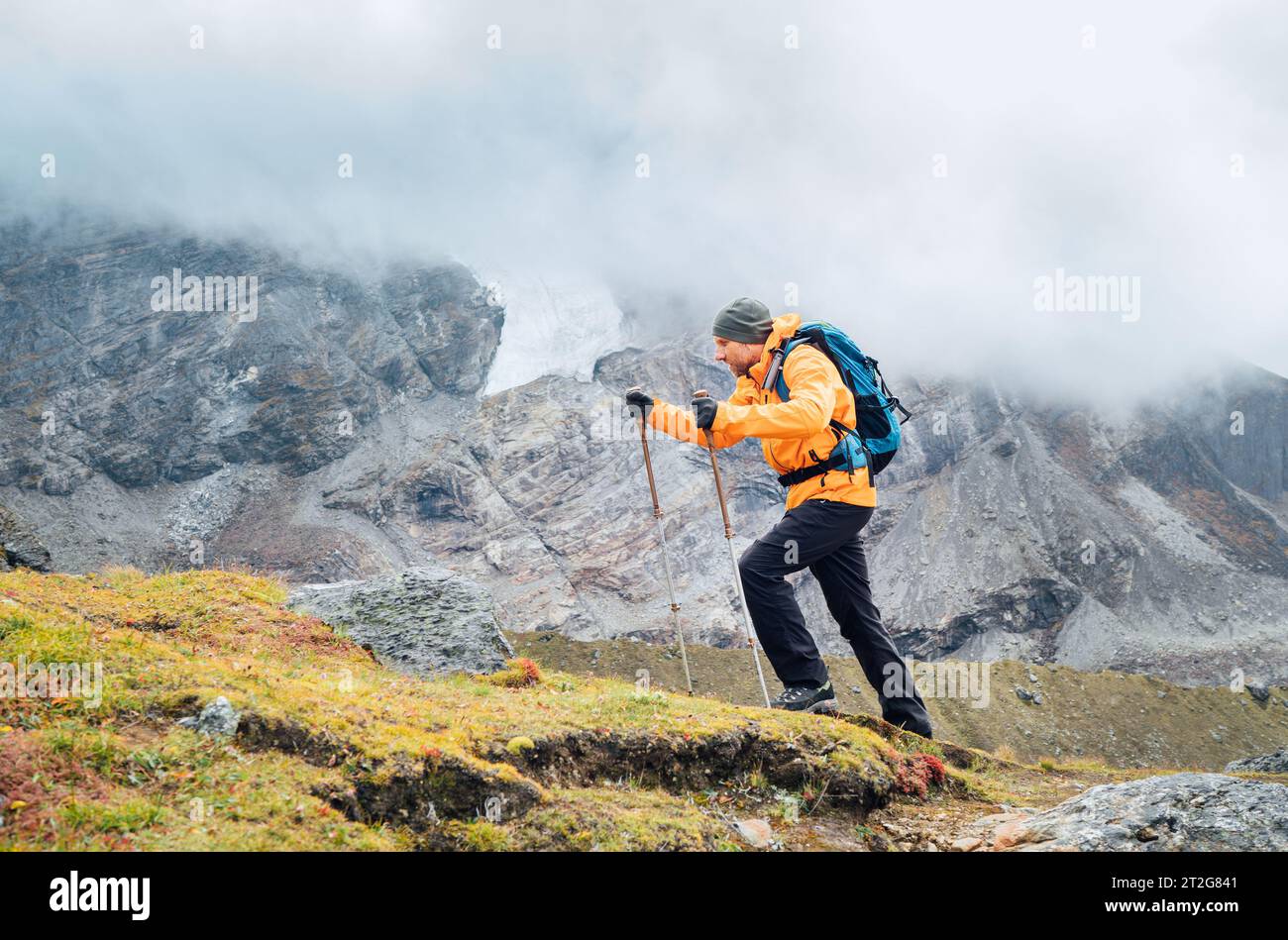 Running caucasian man with backpack and trekking poles by Makalu Barun ...