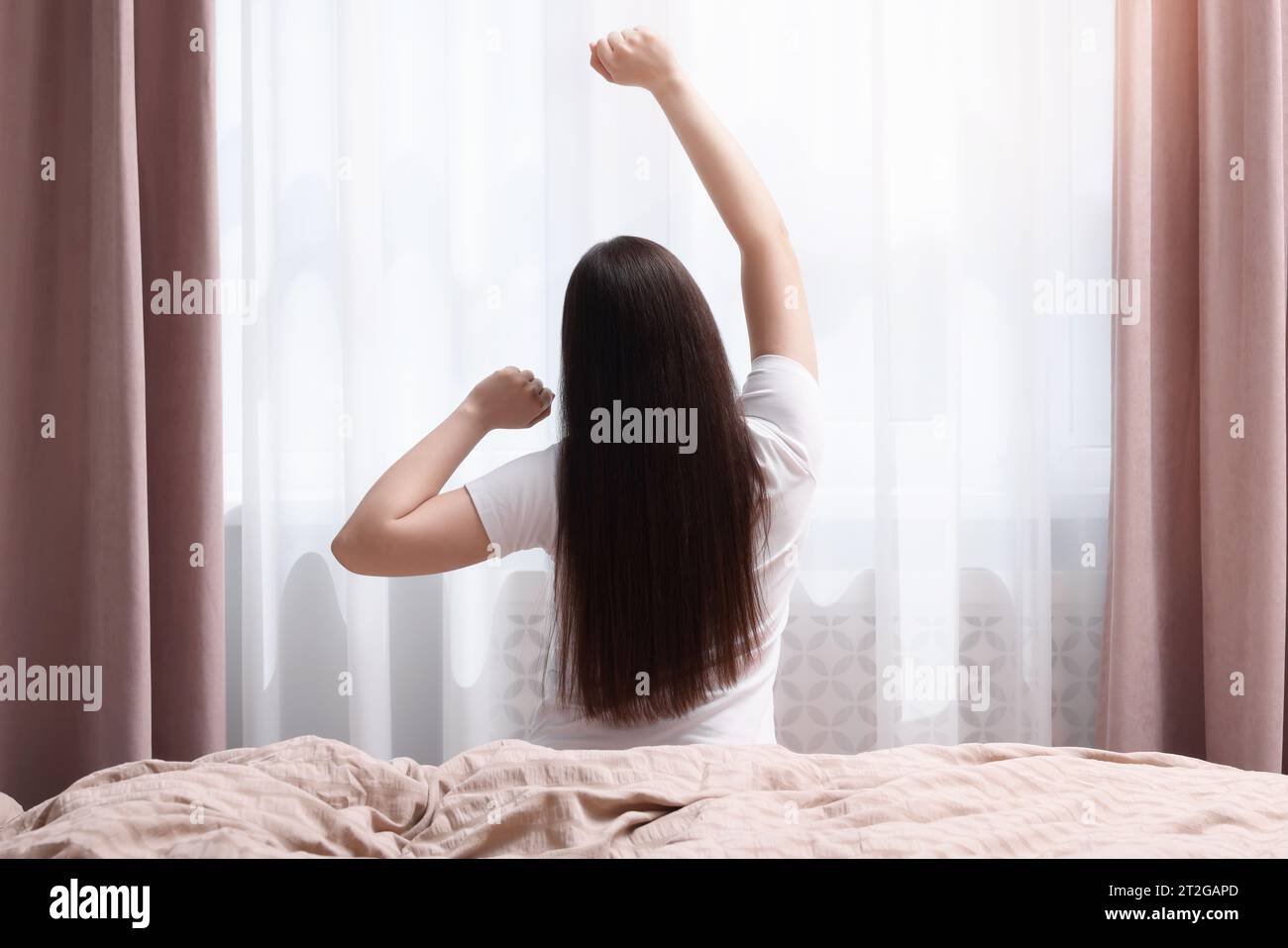 Woman stretching on bed at home, back view. Lazy morning Stock Photo ...