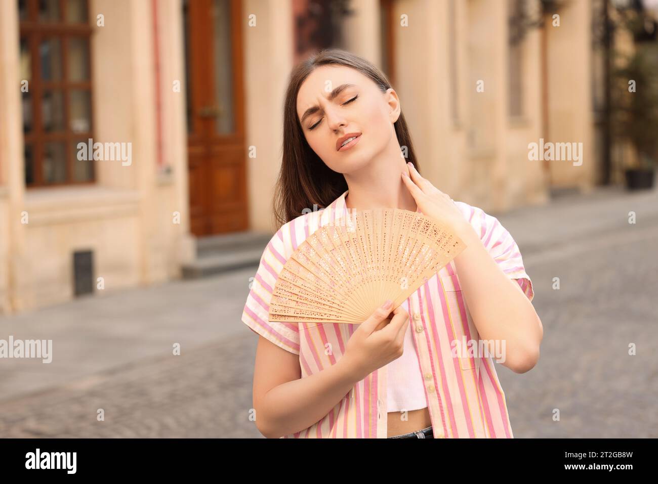 Woman with hand fan suffering from heat outdoors Stock Photo - Alamy