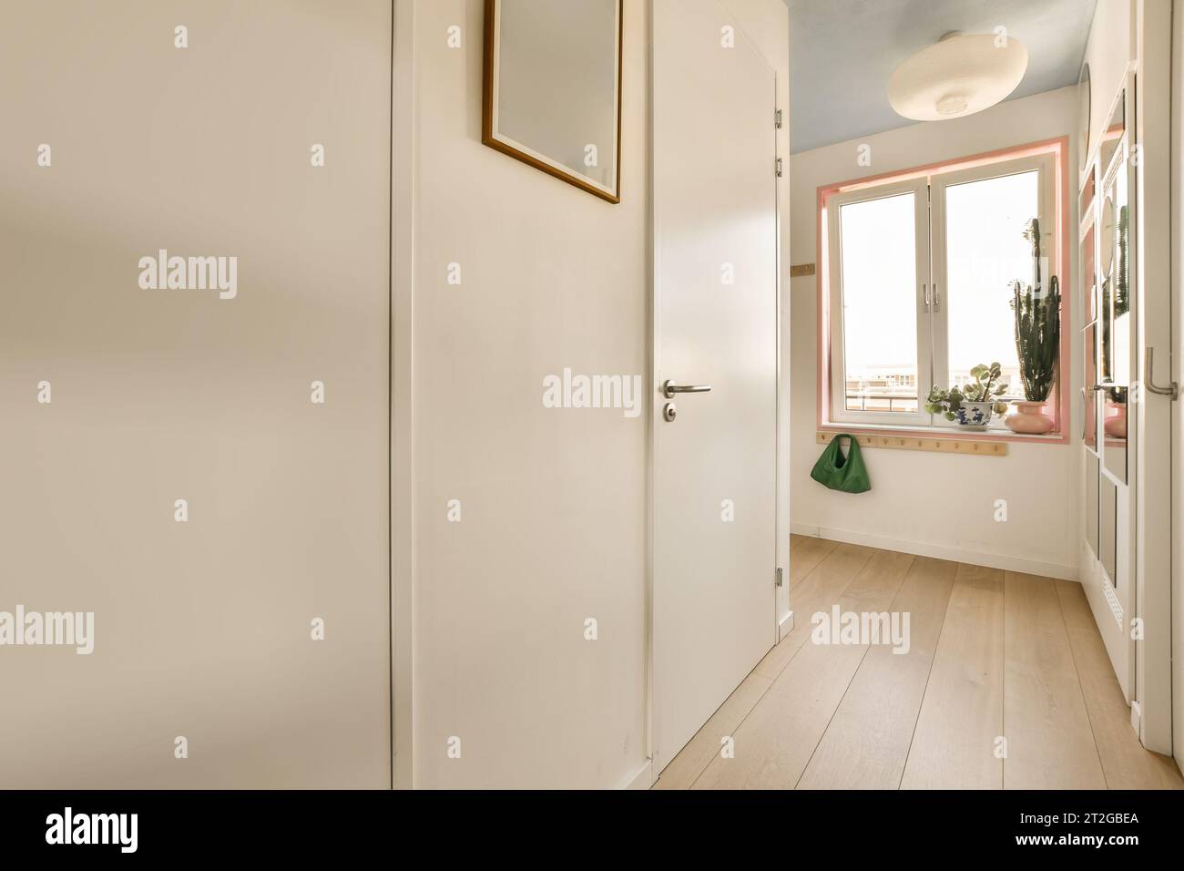 a hallway with white walls and wood flooring on the left side of the ...