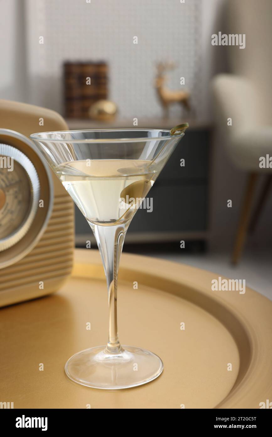 Martini cocktail with olive and retro radio receiver on table in room ...