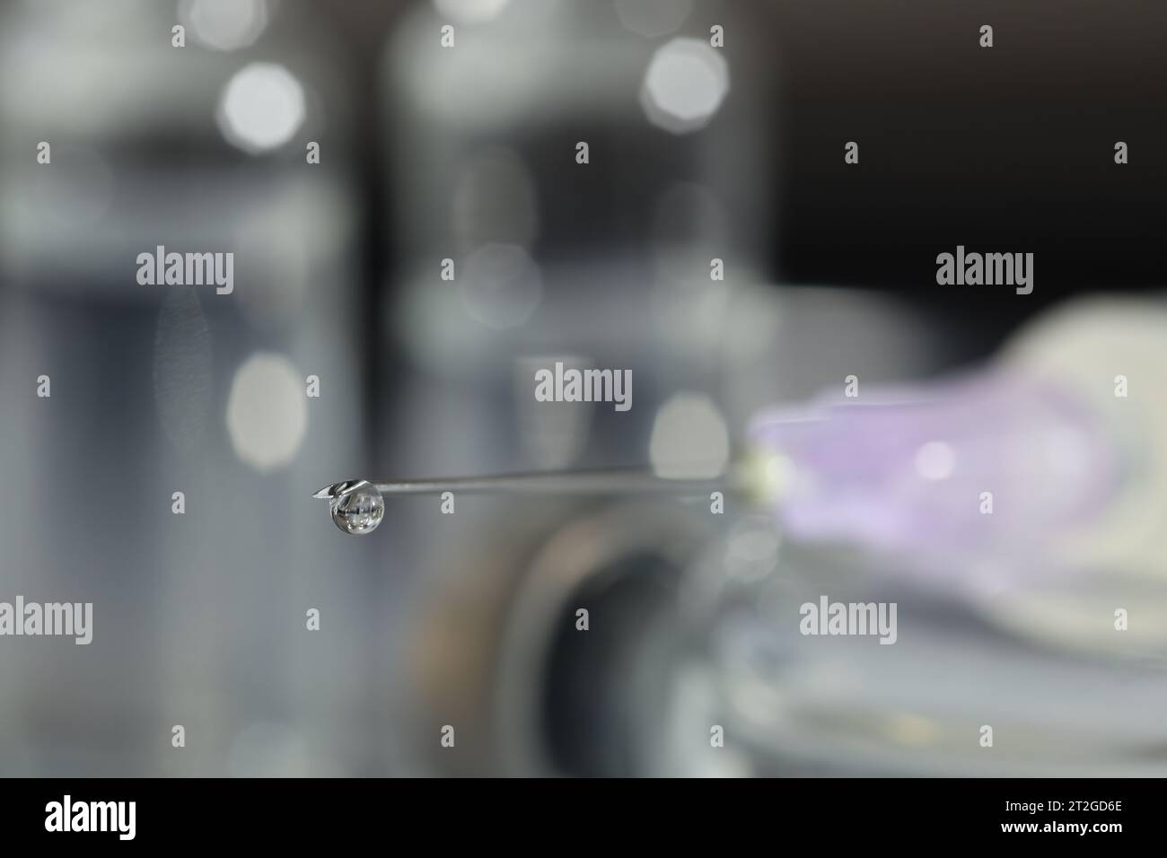 Drop of medication on syringe needle against blurred background ...