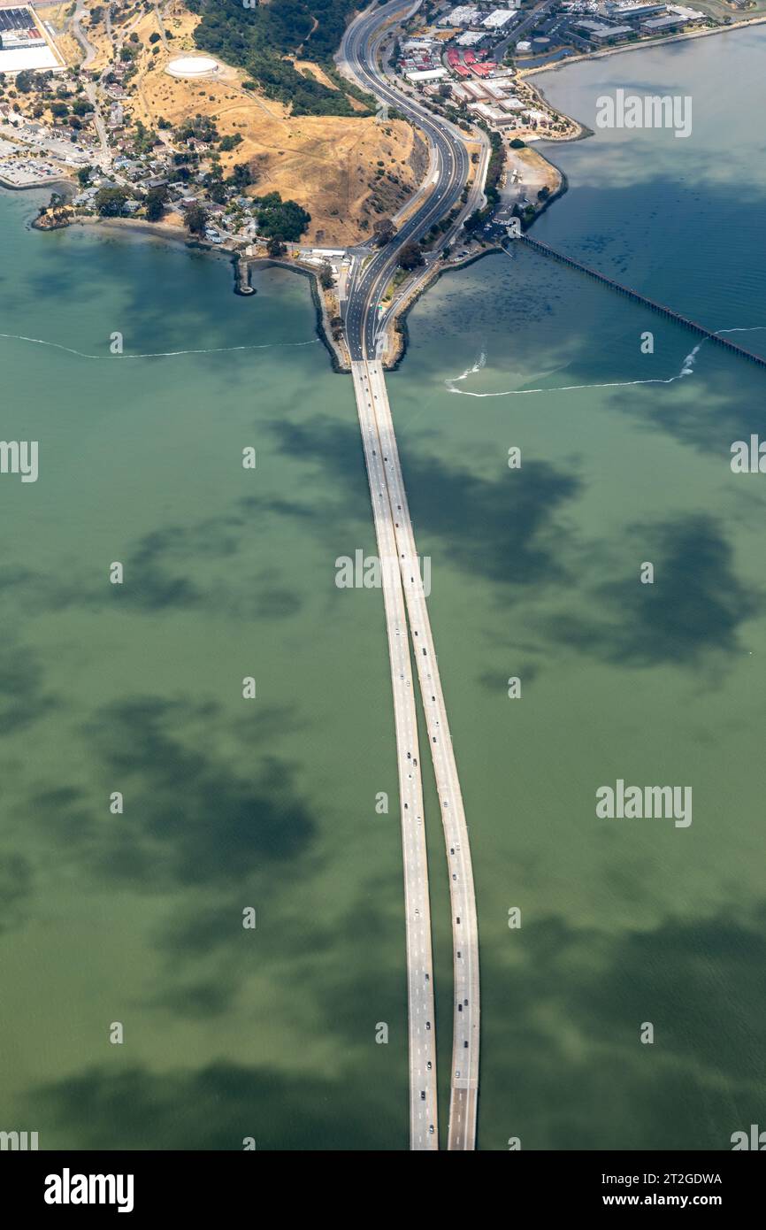 Aerial view of long bridge crossing bay to a peninsula with shadows of ...