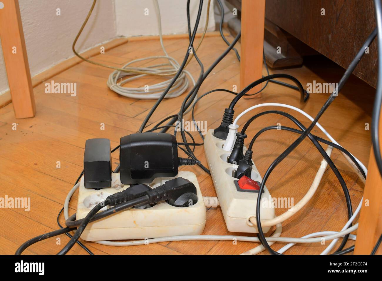 Tangled cables in the extension cord. Messy cables. Cables tangled on parquet flooring Stock ...