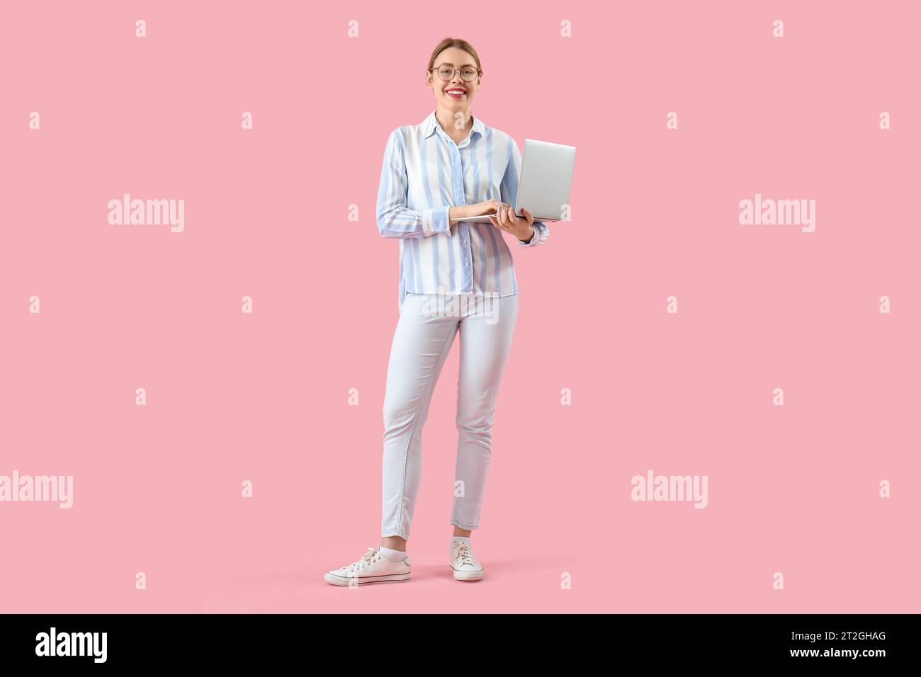 Female programmer working with laptop on pink background Stock Photo ...