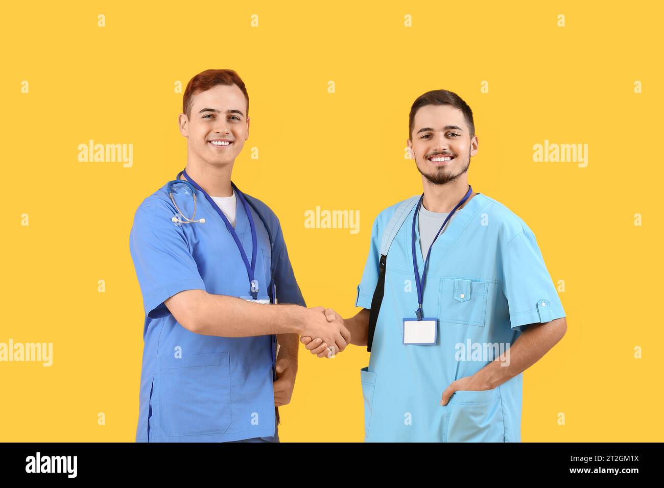 Male medical students shaking hands on yellow background Stock Photo ...