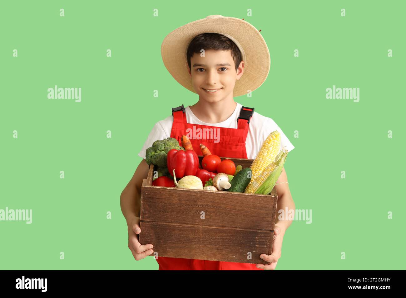 Little farmer with fresh food on green background Stock Photo - Alamy