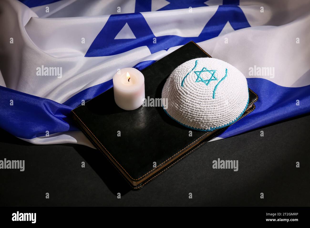 Torah with Jewish hat, burning candle and flag of Israel on dark ...