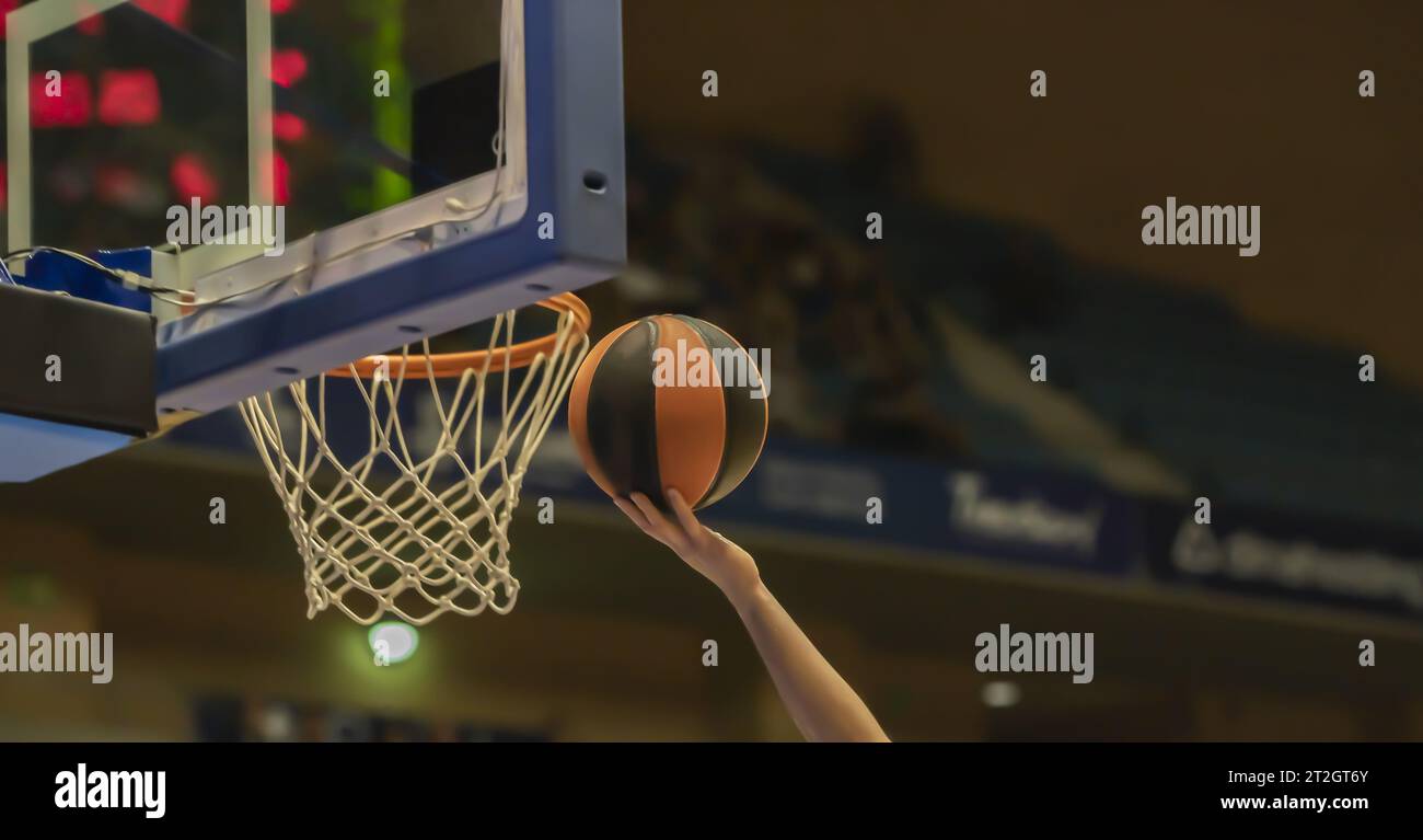 close-up of a hand clapping a basketball with the stands of the stadium ...