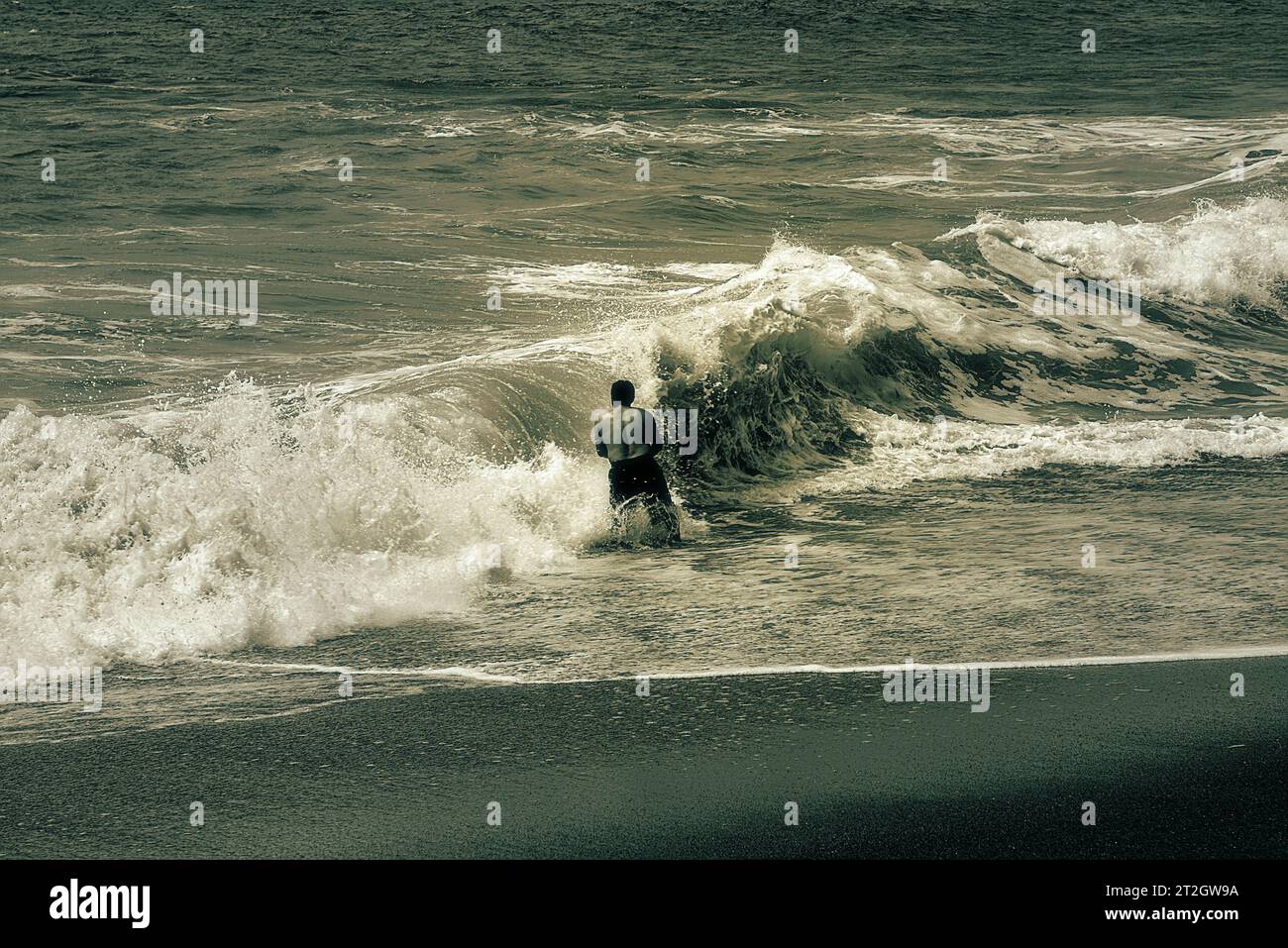 Waves of the ocean hitting a man. Monocrome shut close to the golden ...