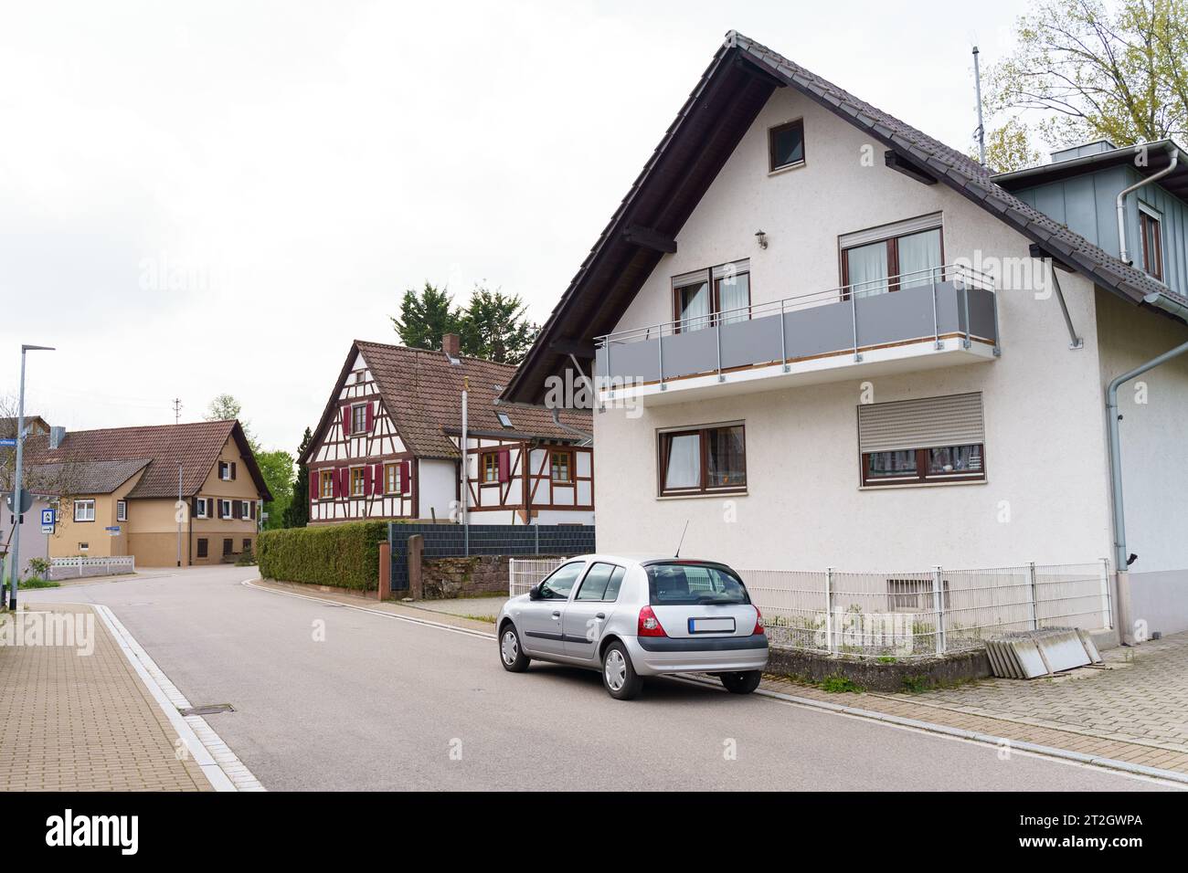 An empty street in a German village, a car is parked next to the house ...