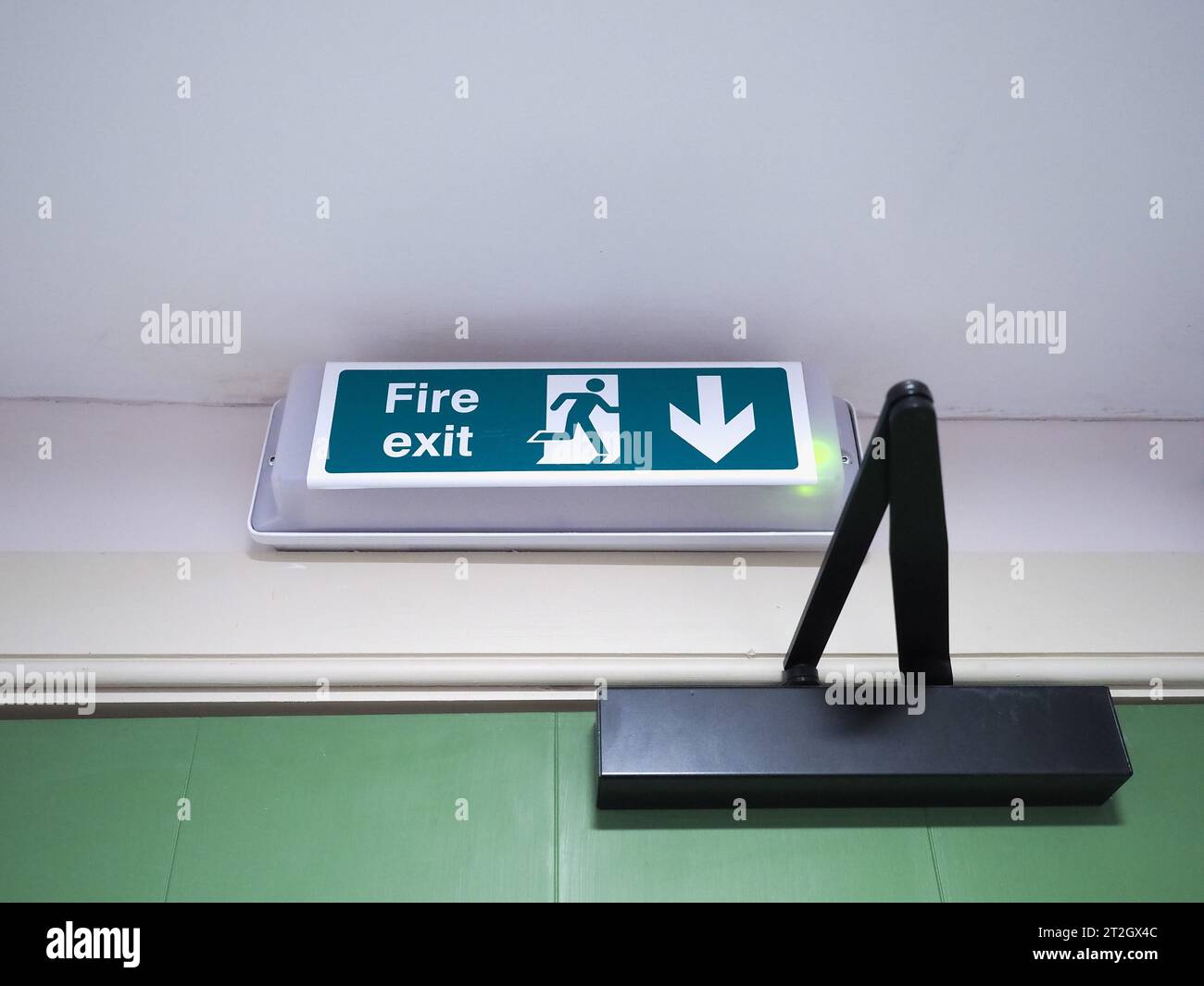 fire exit sign above green wooden door Stock Photo - Alamy