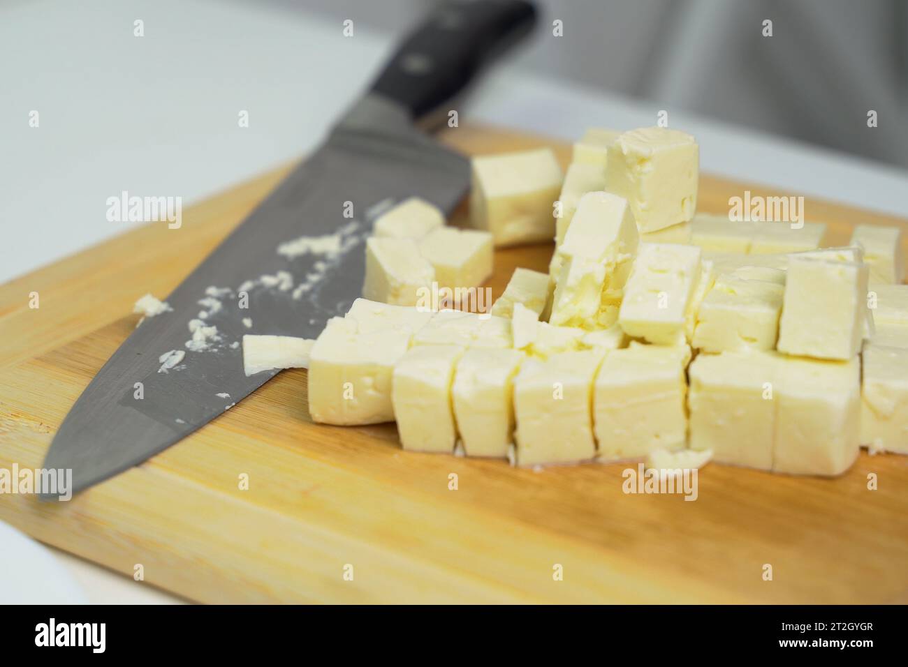 There is diced feta cheese and a knife on the kitchen board. Close-up ...