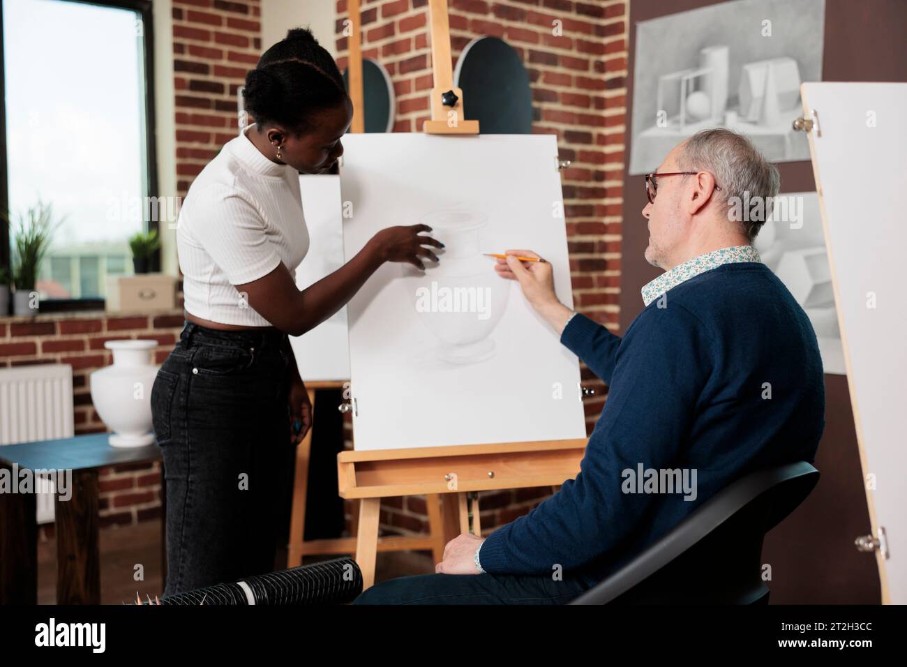 Diverse different aged art school students communicating during drawing ...